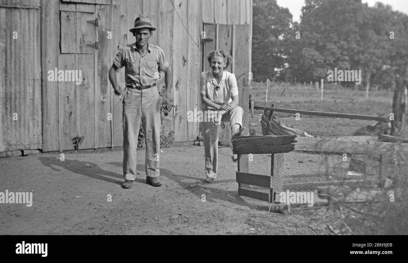 Man and woman stand and pose for photo in front of their barn on a farm ...