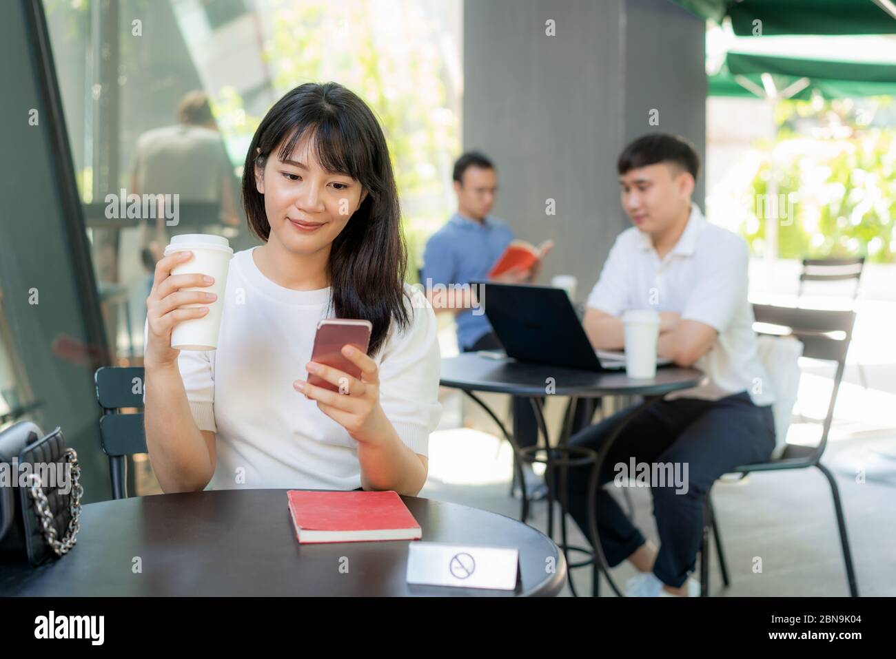 Asian young man and woman sitting one person per one table for distance ...