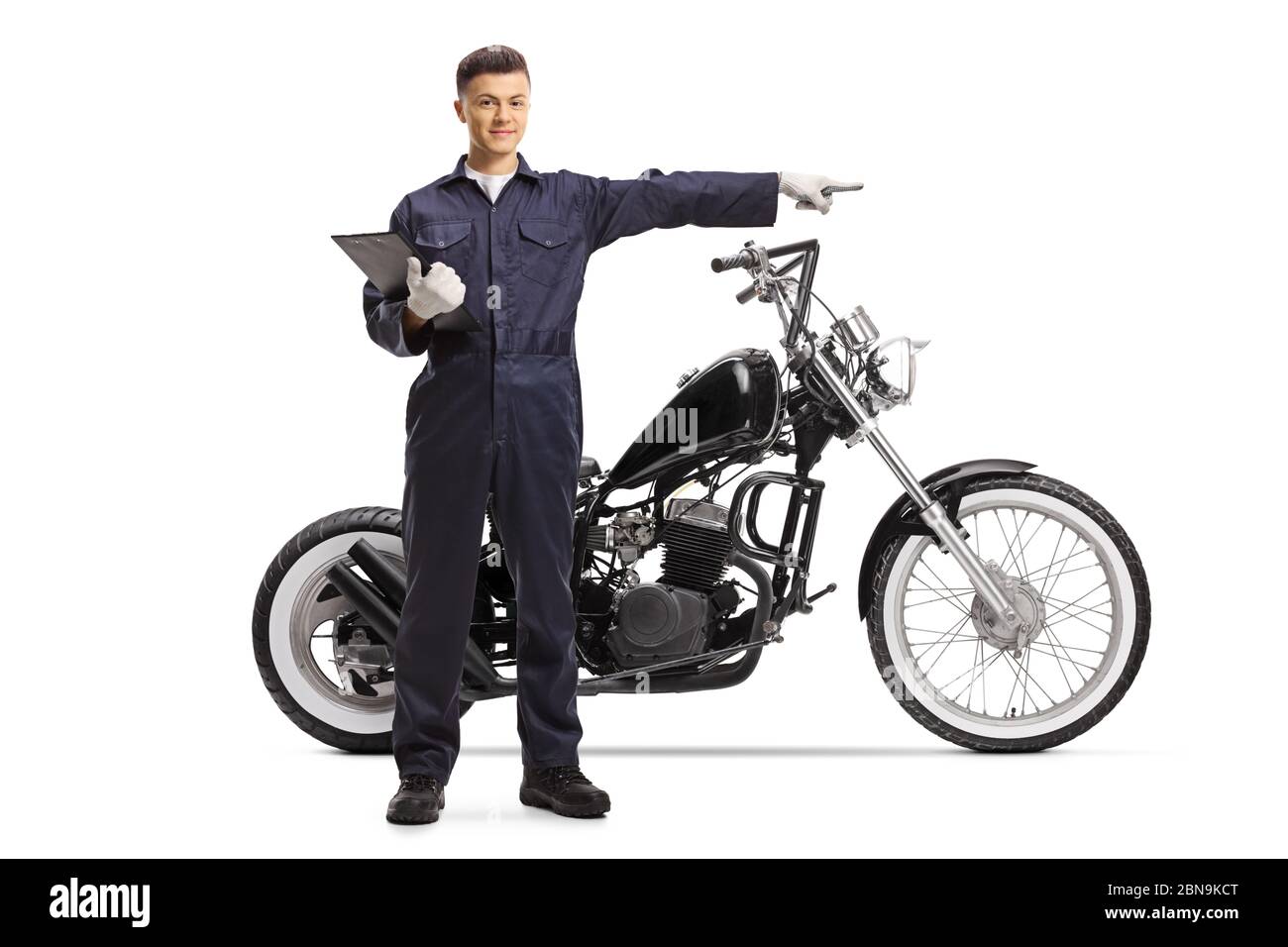 Full length portrait of a mechanic standing next to a chopper motorbike ...