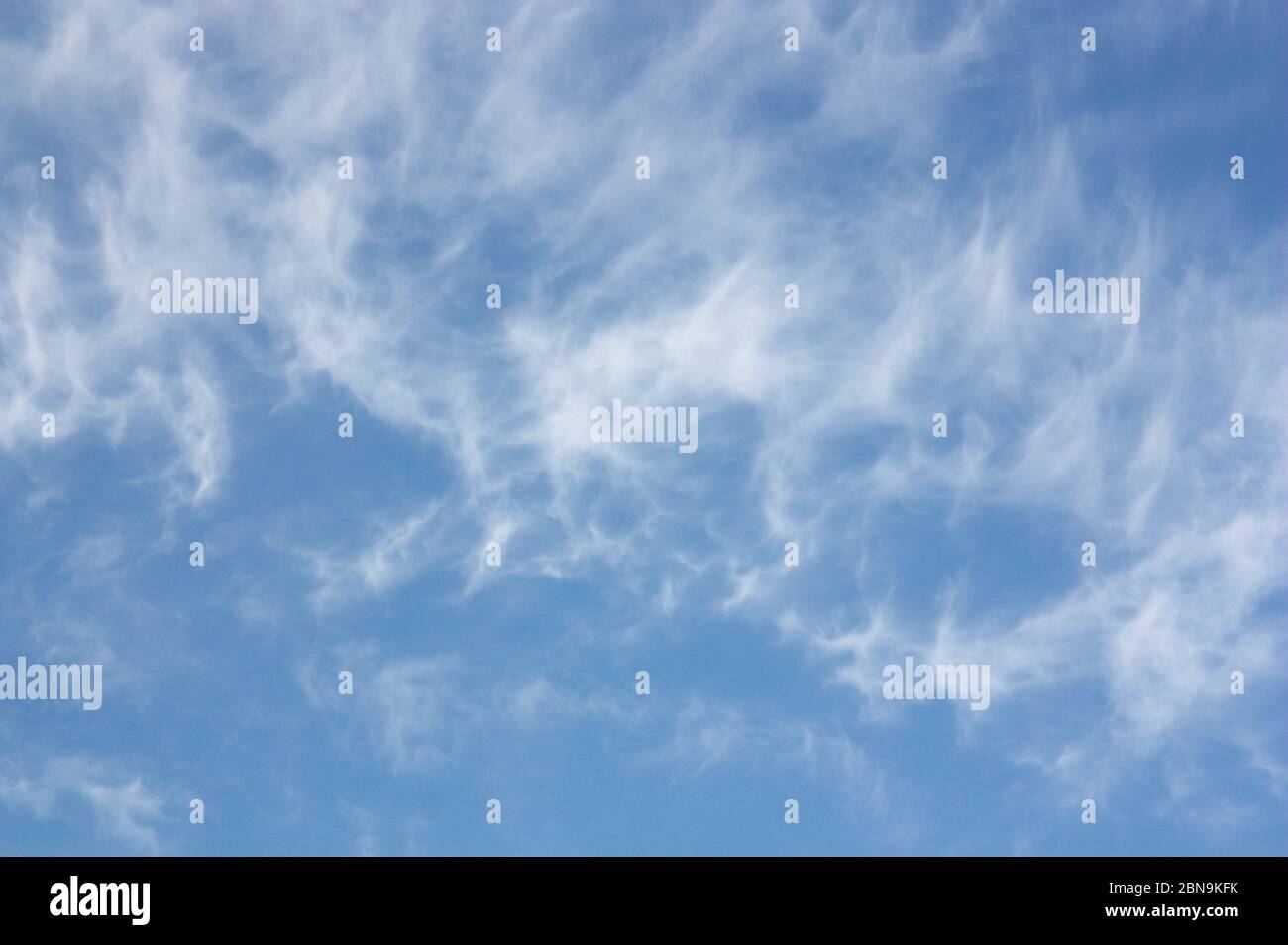 Image of a few separate clouds that form white and fibrous filaments ...