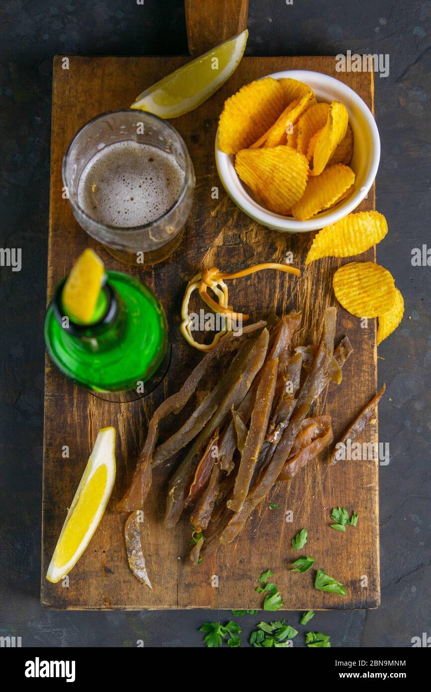 Dried carp fish sticks with beer, lemon and potato chips on dark wooden ...