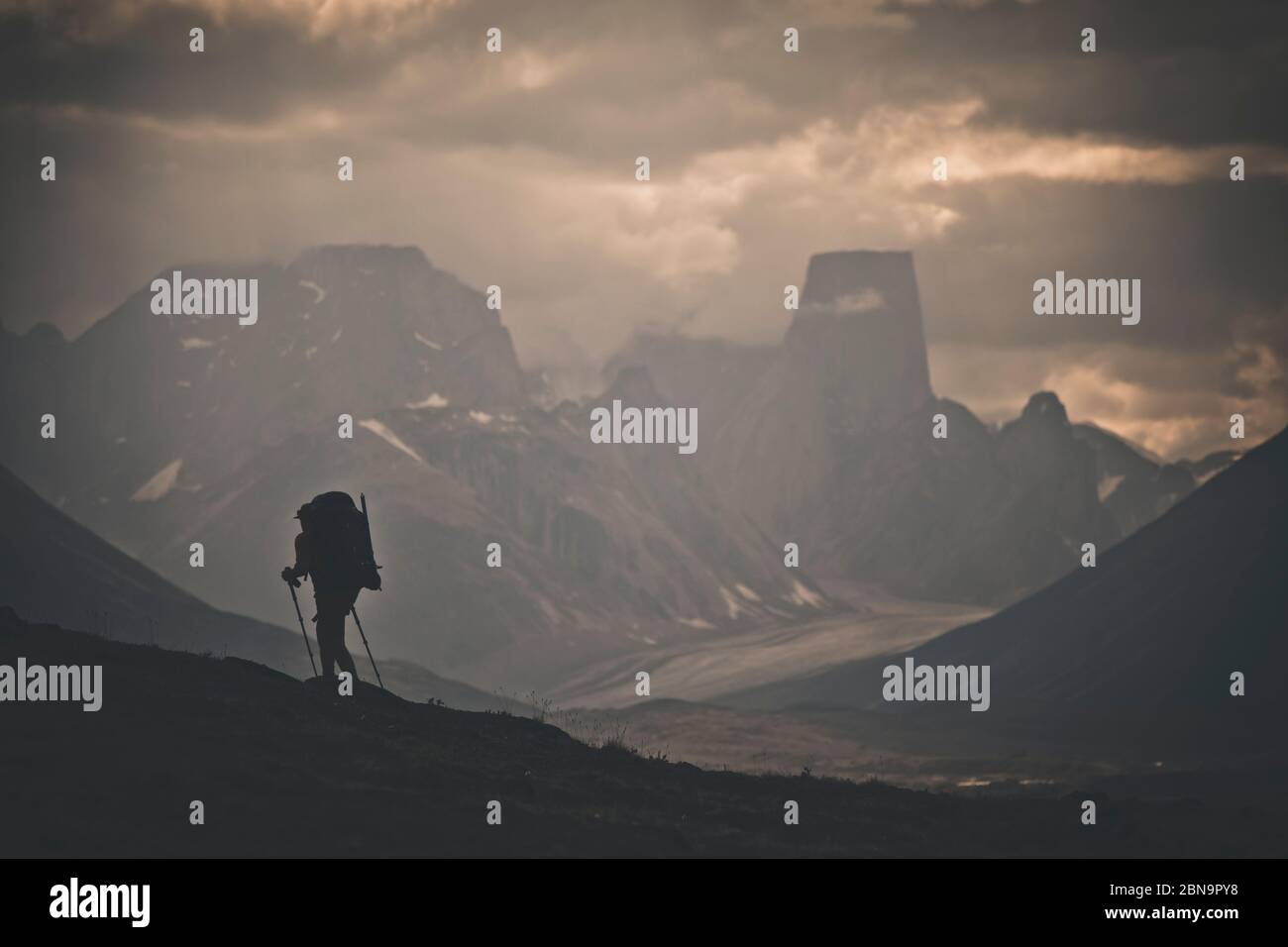 Silhouette of backpacker hiking through rugged mountain landscape Stock ...