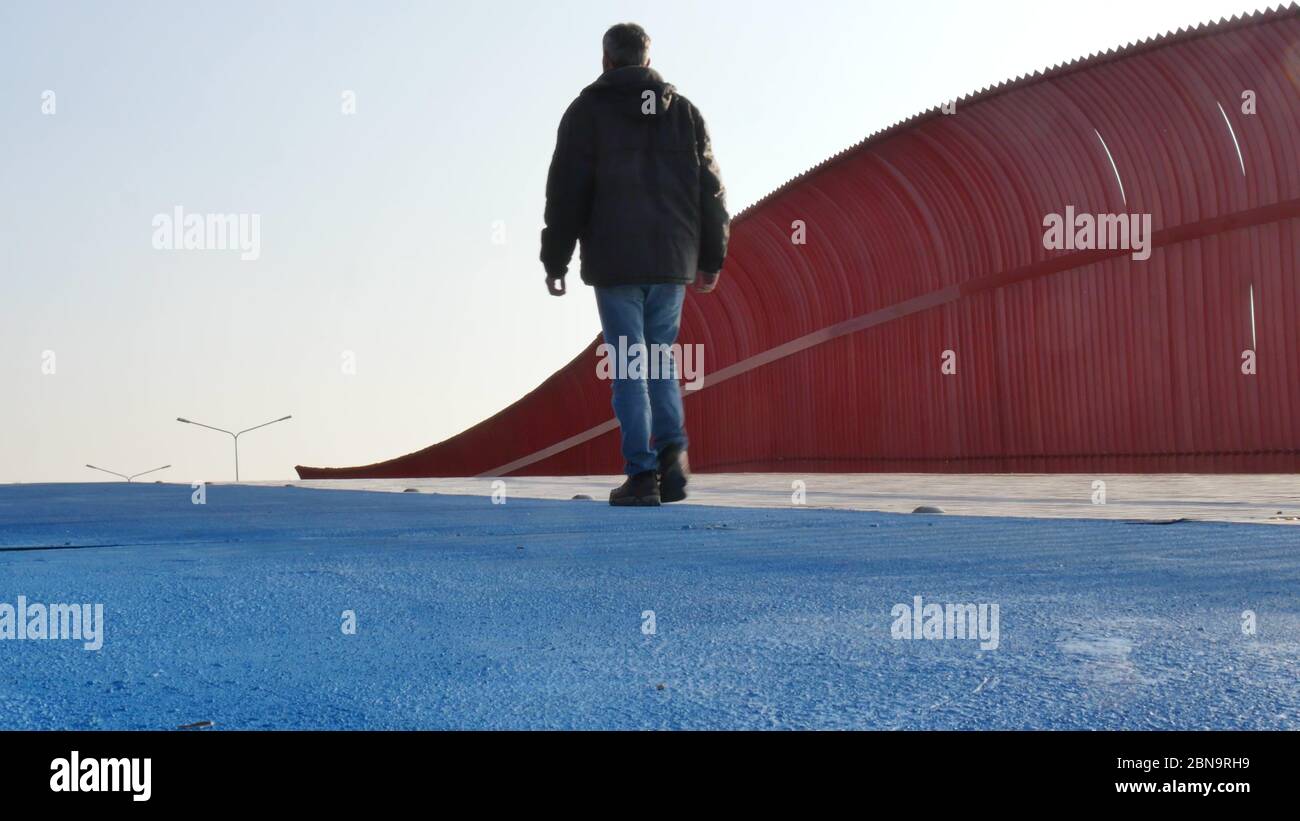 Man walking alone on empty street or bridge. Back view. Traveling the ...