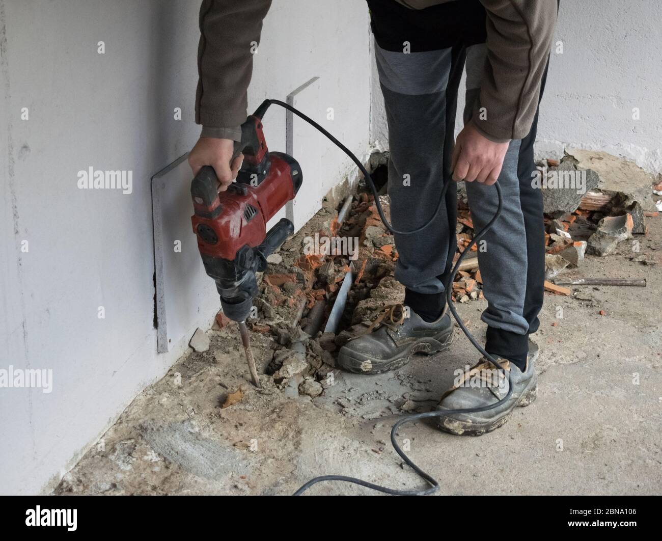 High angle shallow focus shot of a male worker drilling the ground ...