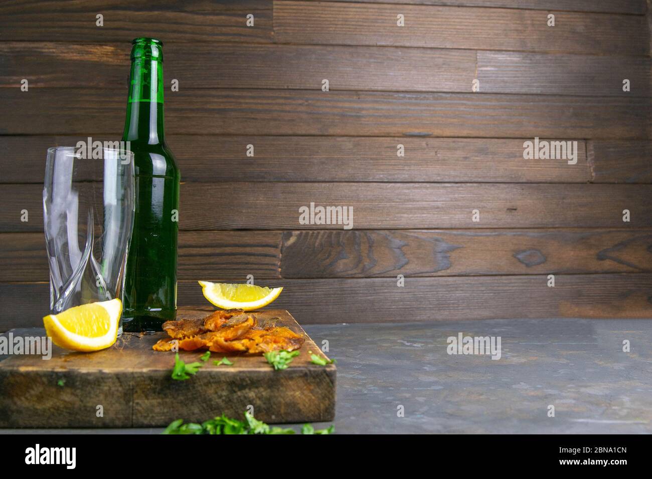 Dried perch with beer, lemon and potato chips on dark wooden board ...