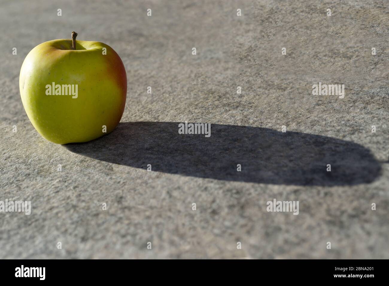 Closeup of an apple and its shadow on a concrete surface Stock Photo ...