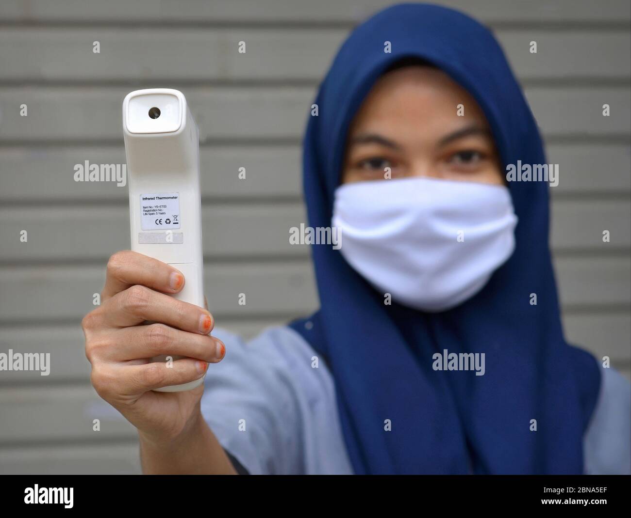 Muslim Malay girl with hijab and mouth-covering veil takes forehead ...