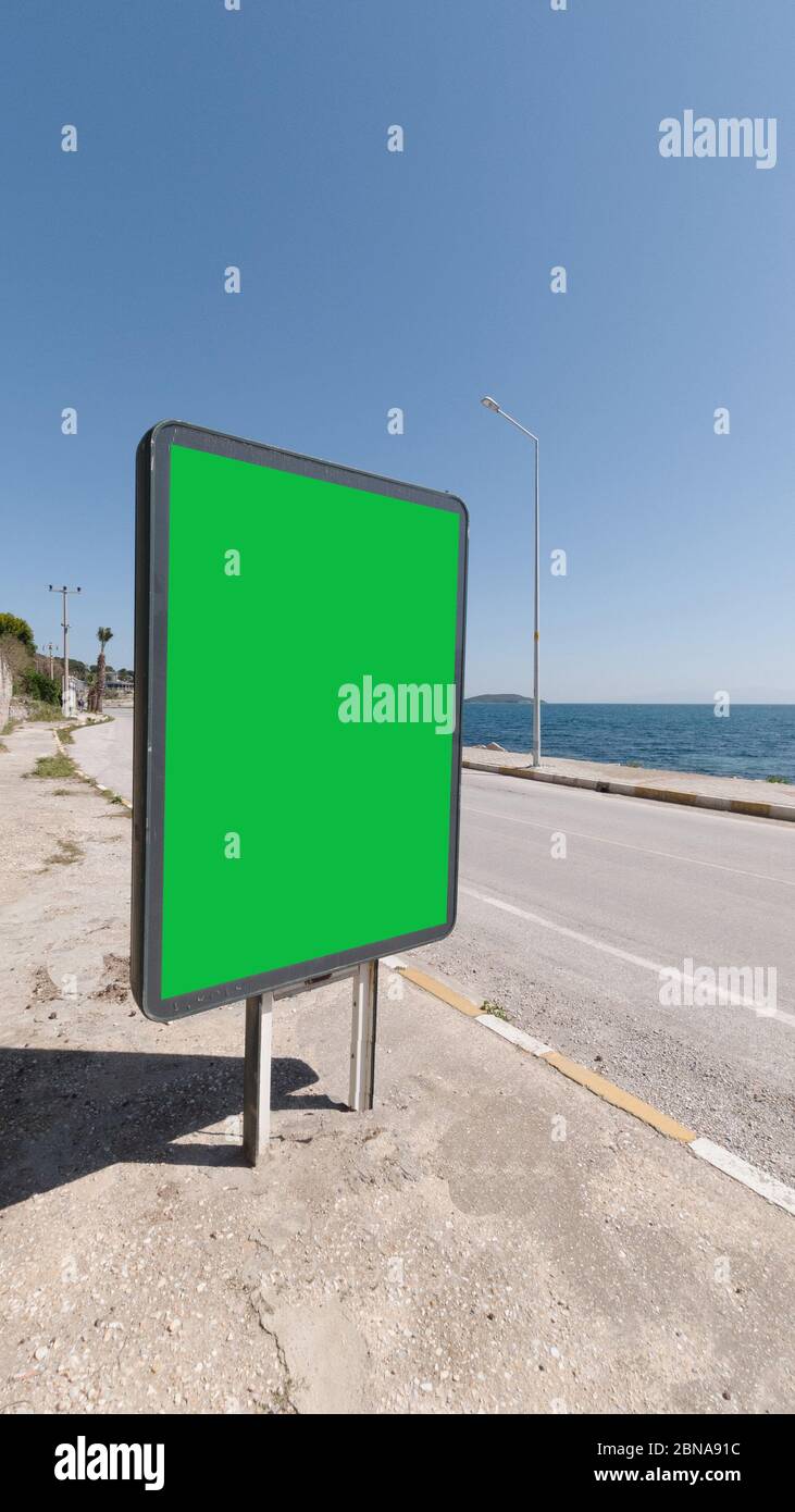 Vertical image of a green screen for ads at the side of a road, an ...