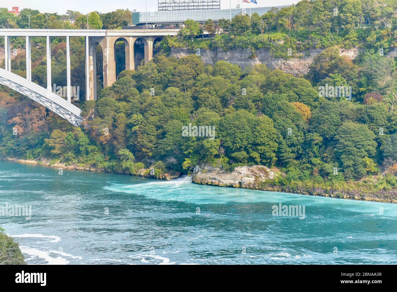 Beautiful view of a bridge over the river by the green trees captured ...