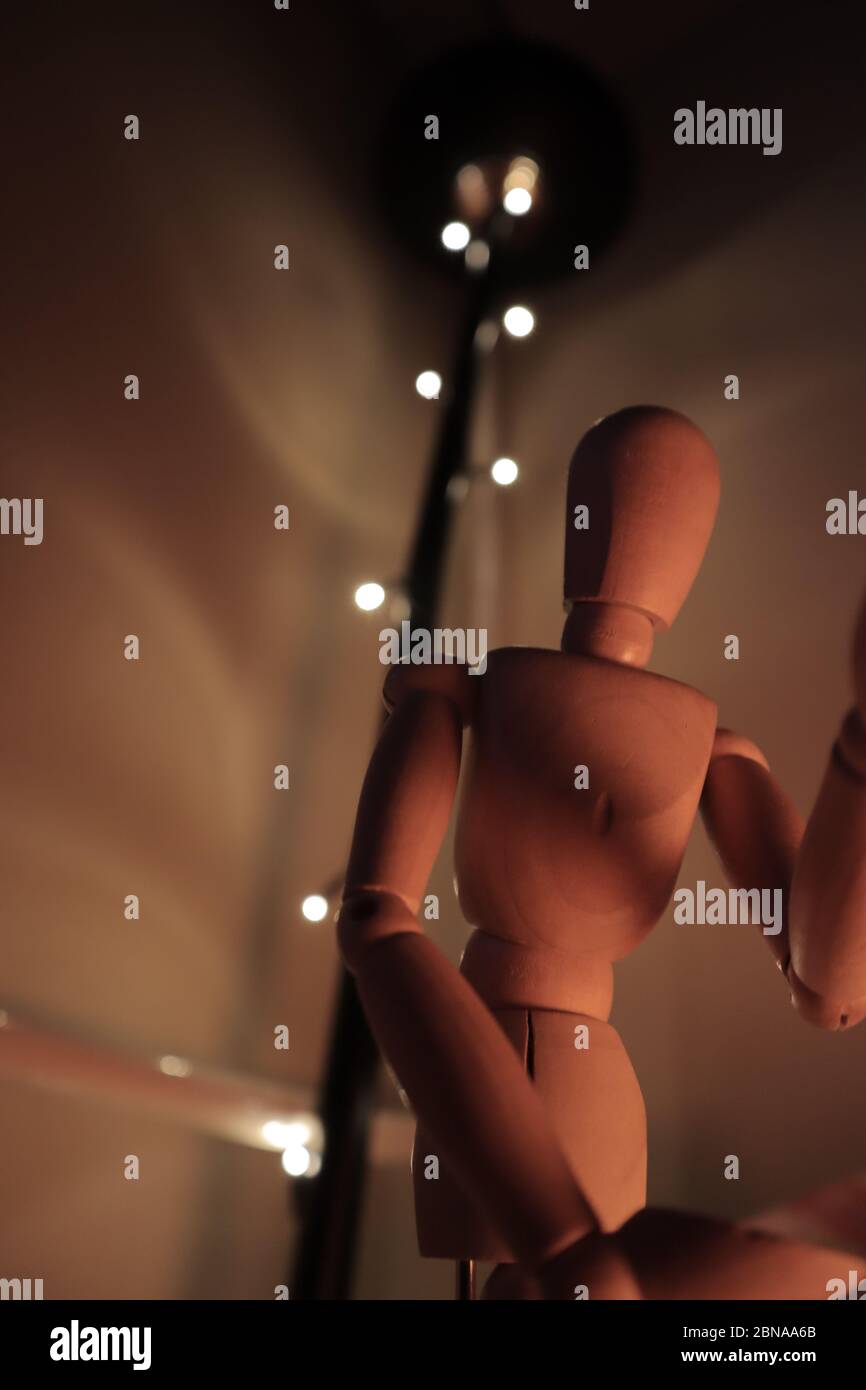 Vertical closeup shot of a wooden figure in a moving pose under lights ...