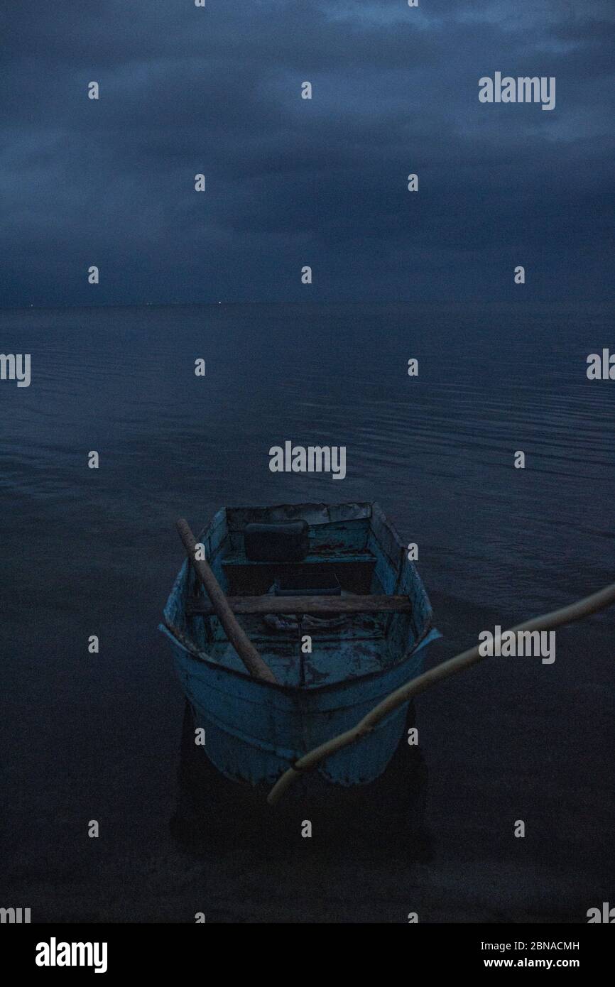 Eerie shot of a docked small blue boat in the sea on a gloomy day Stock ...