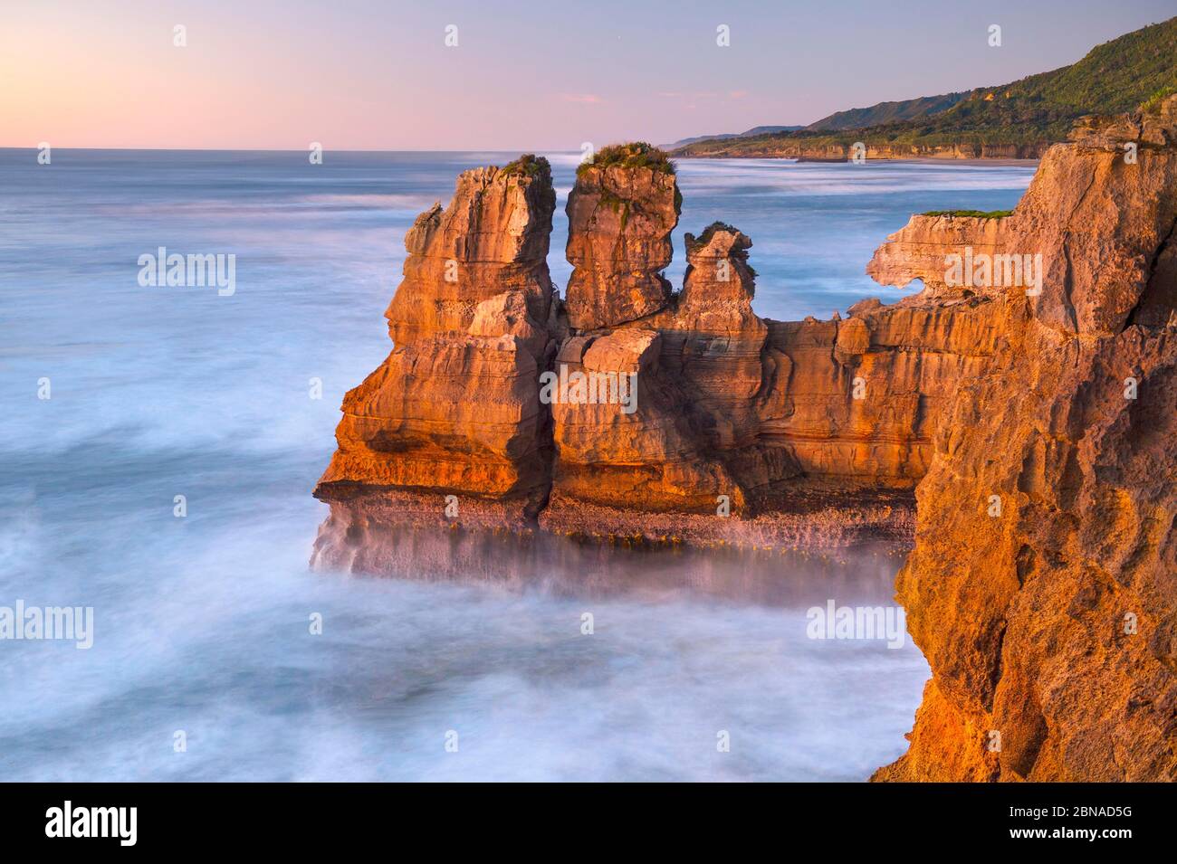 Rock formations on the coast of Paparoa National Park in red evening ...