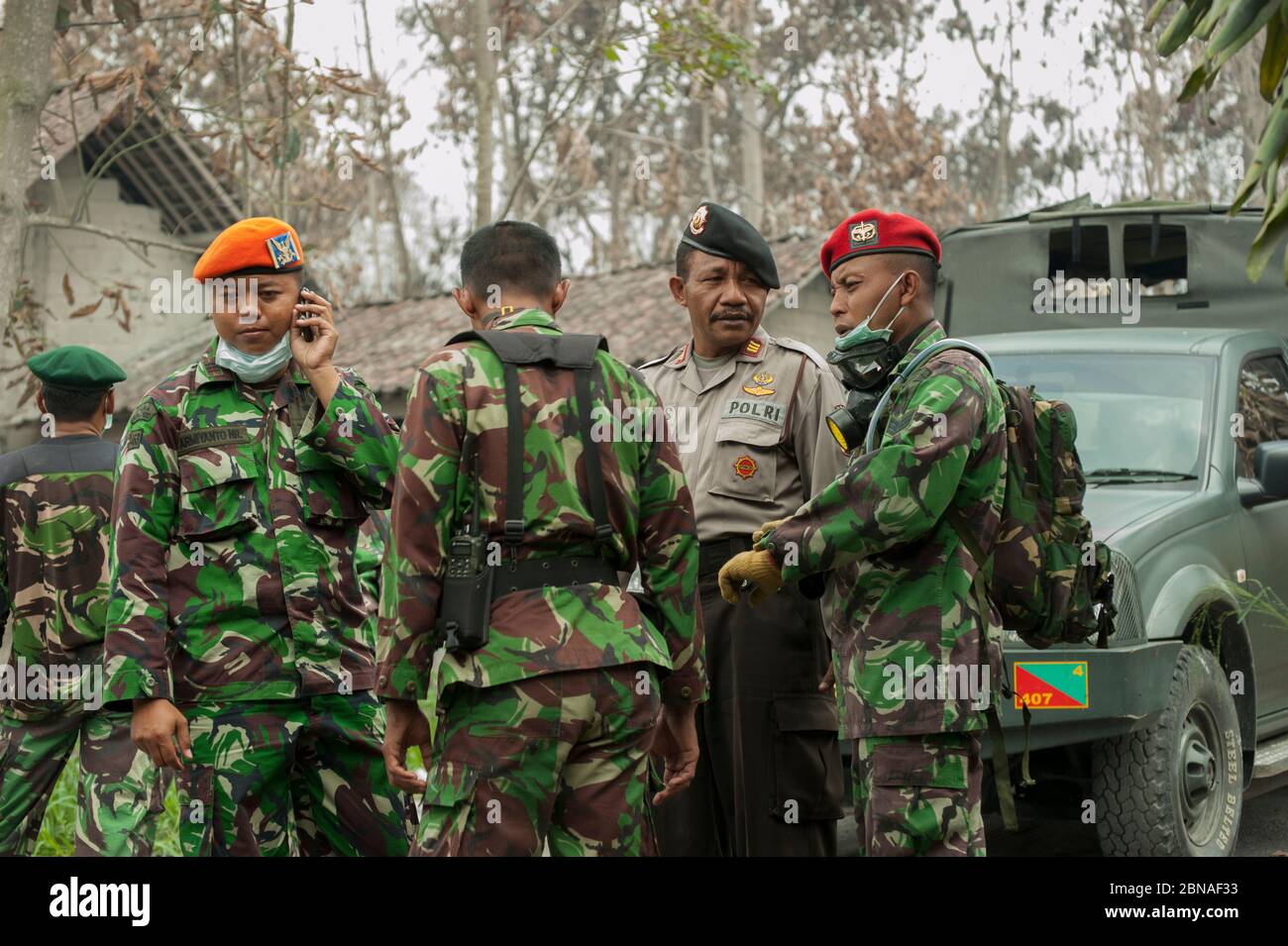 Army soldiers and police wearing masks on road outside building damaged ...