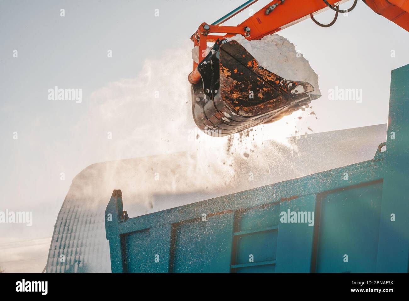 Snow removal after snowfall and blizzards. Excavator loads snow into a ...