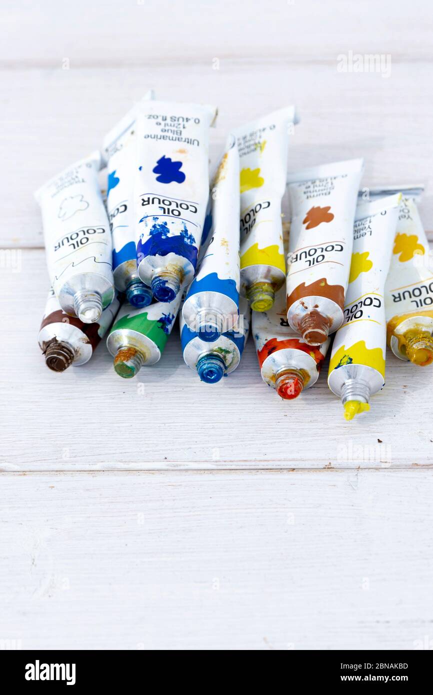 Artist oil paint tubes in various colours on white wood. Art and craft ...