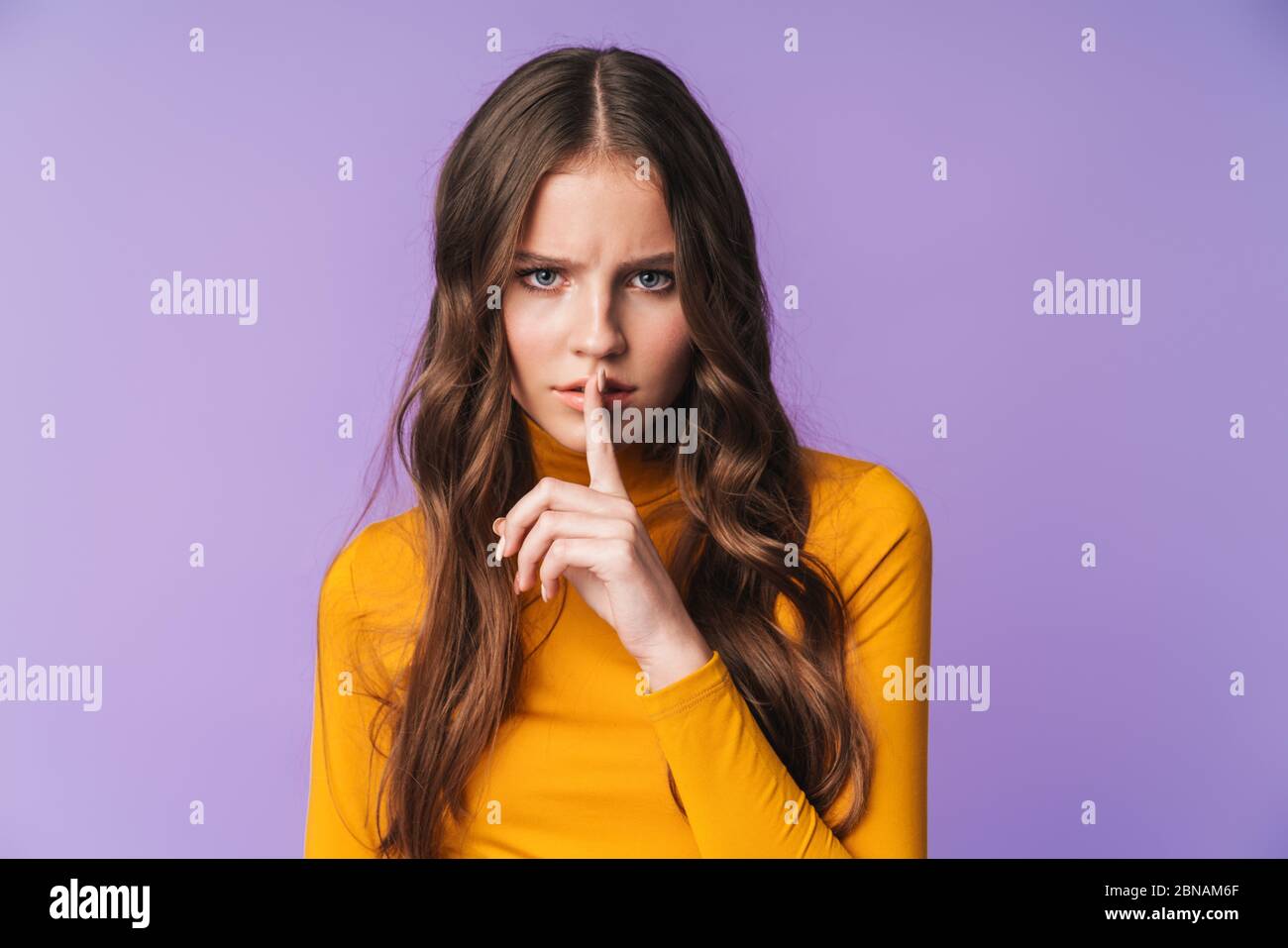 Image of young beautiful woman with long brown hair frowning and doing ...