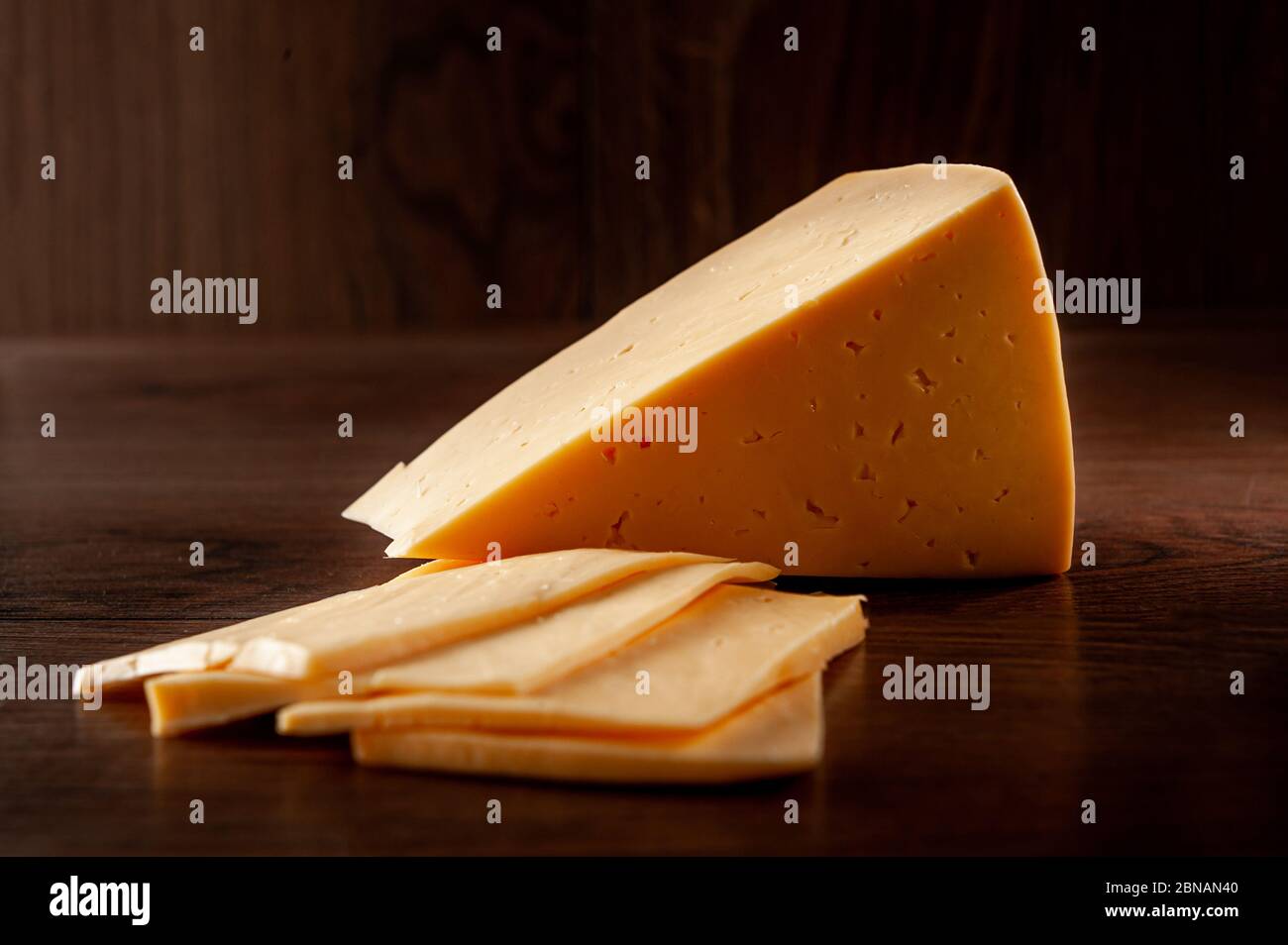 ordinary cheese on a wooden background sliced with slices lies on the ...