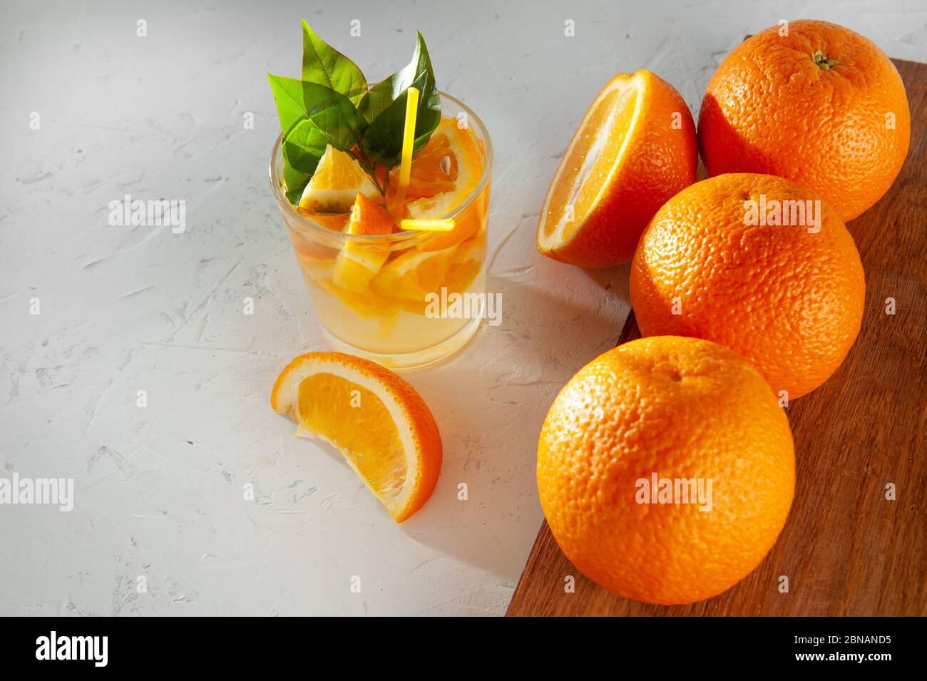 water with orange slices in a glass of green leaves on a white ...