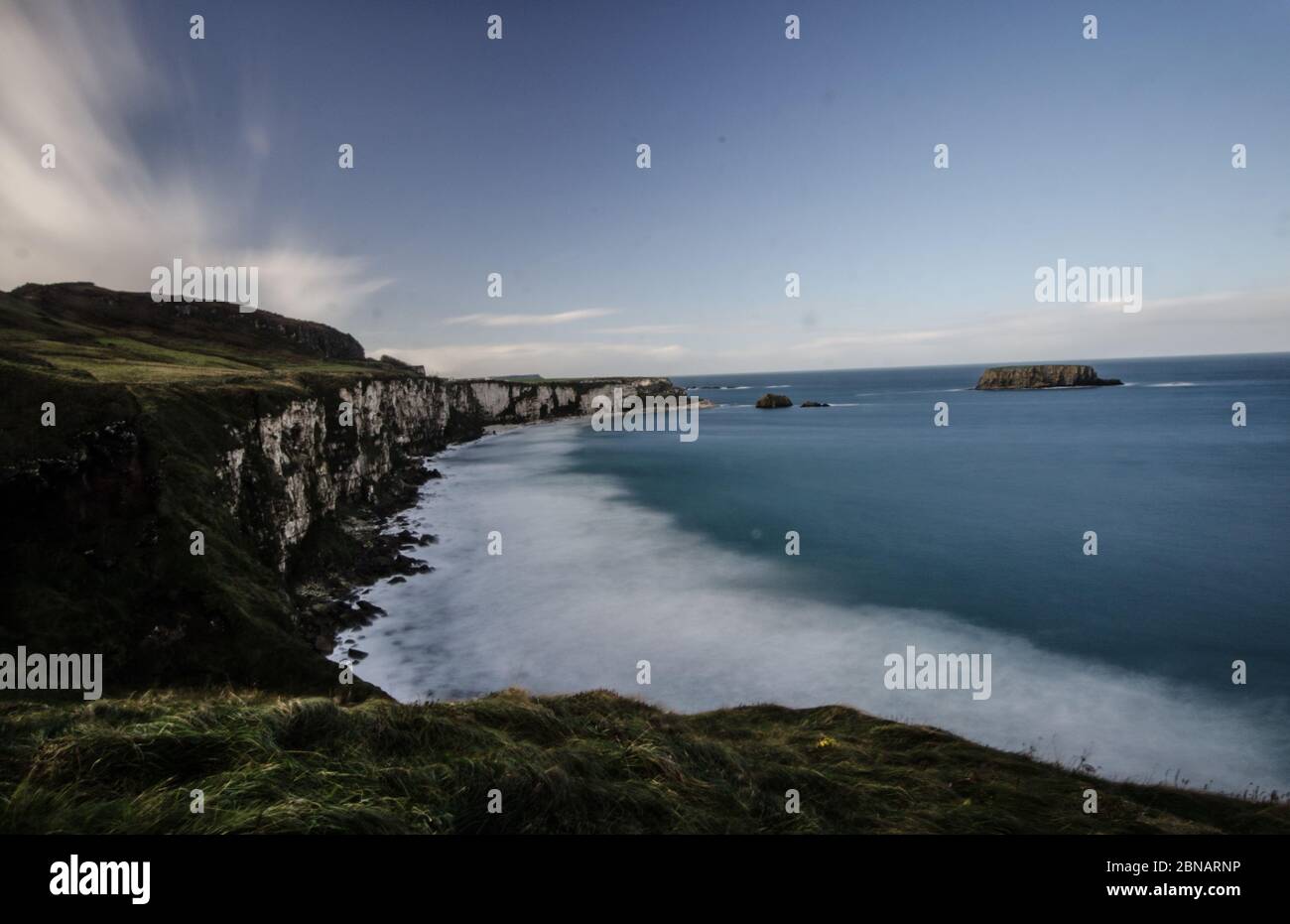 Beautiful view of the grass-covered cliffs by the calm ocean under the ...