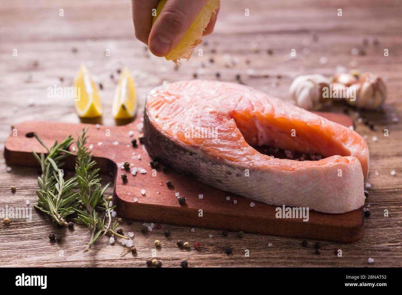 Squeezing fresh lemon juice on the fillets of salmon fish, close-up ...