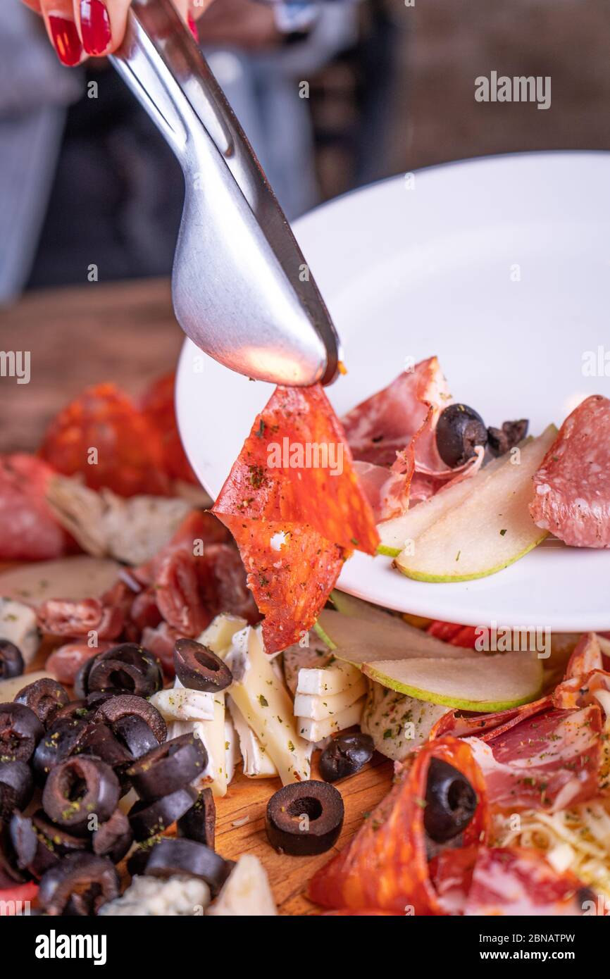 Person putting a variety of meat assortment on the plate Stock Photo ...
