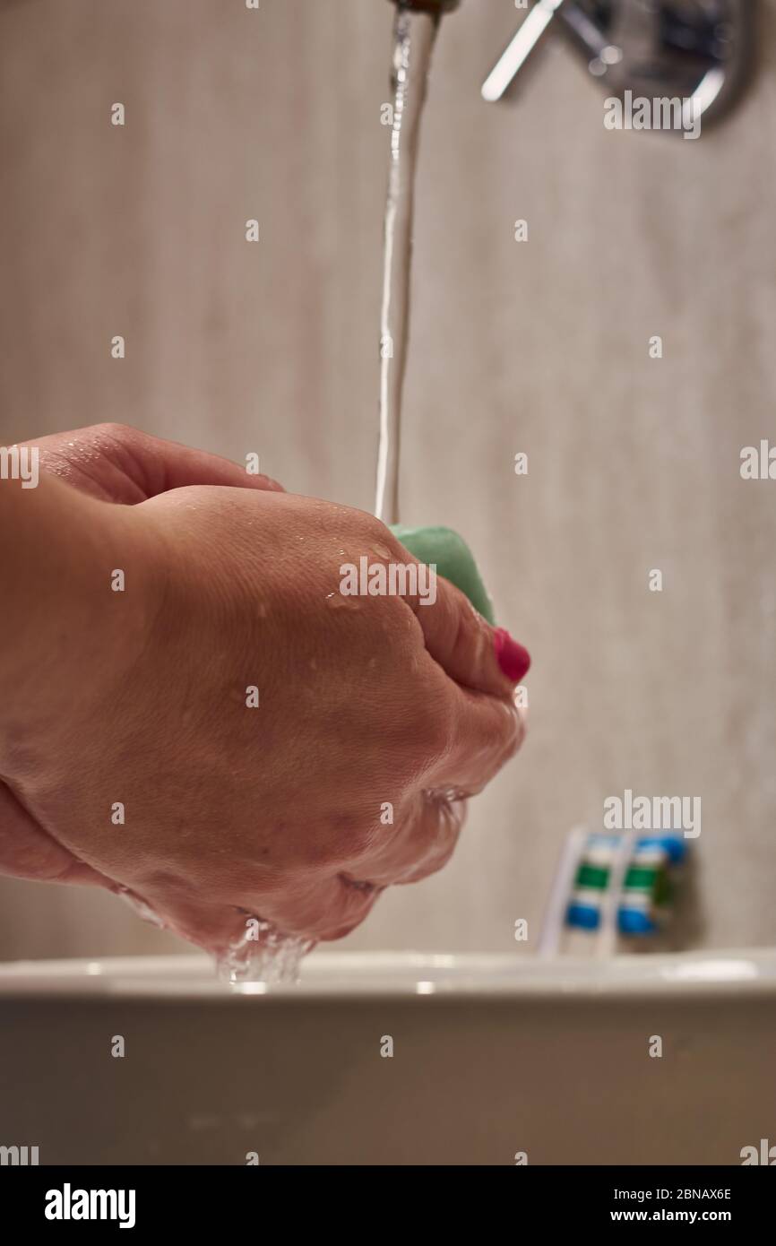 Vertical closeup of a female washing her hands with soap under the ...