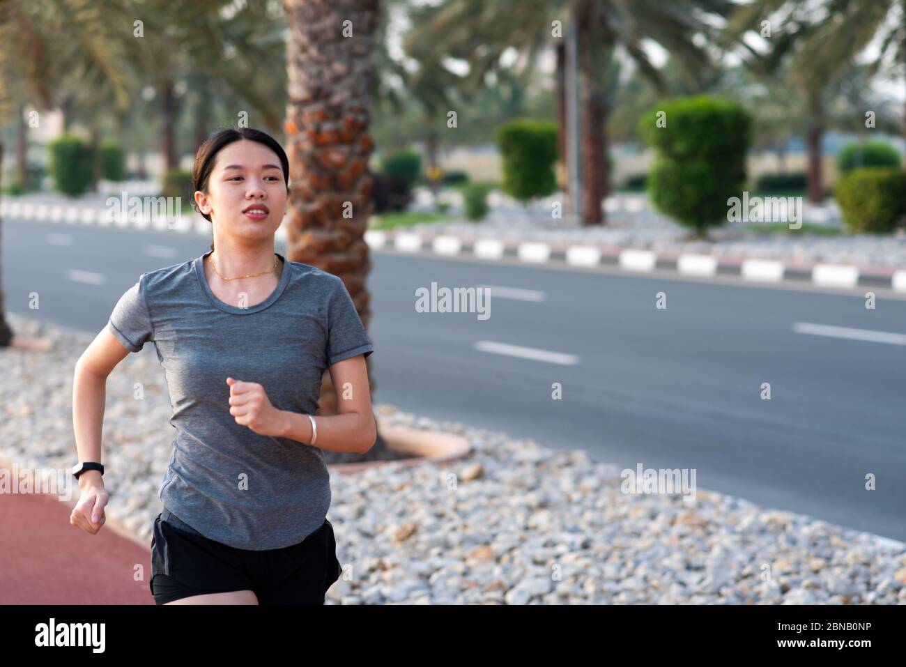 Asian woman jogging on the running track outdoors to maintain fitness ...