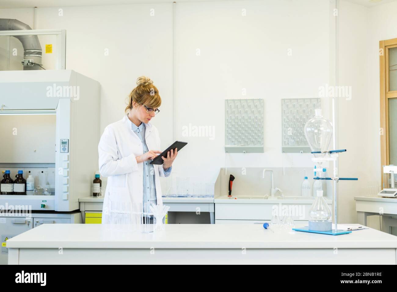 Female chemical scientist holds finger over blank tablet screen in ...