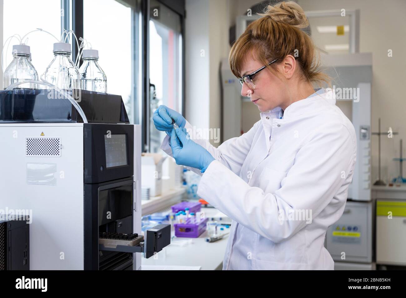 Female chemical scientist wearing glasses and rubber gloves takes ...