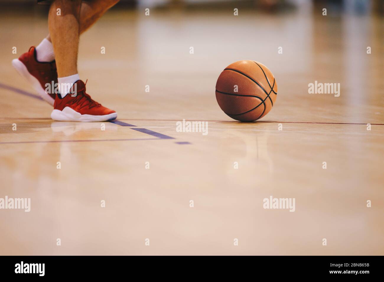 Basketball player walking on wooden court. Basketball over the floor ...