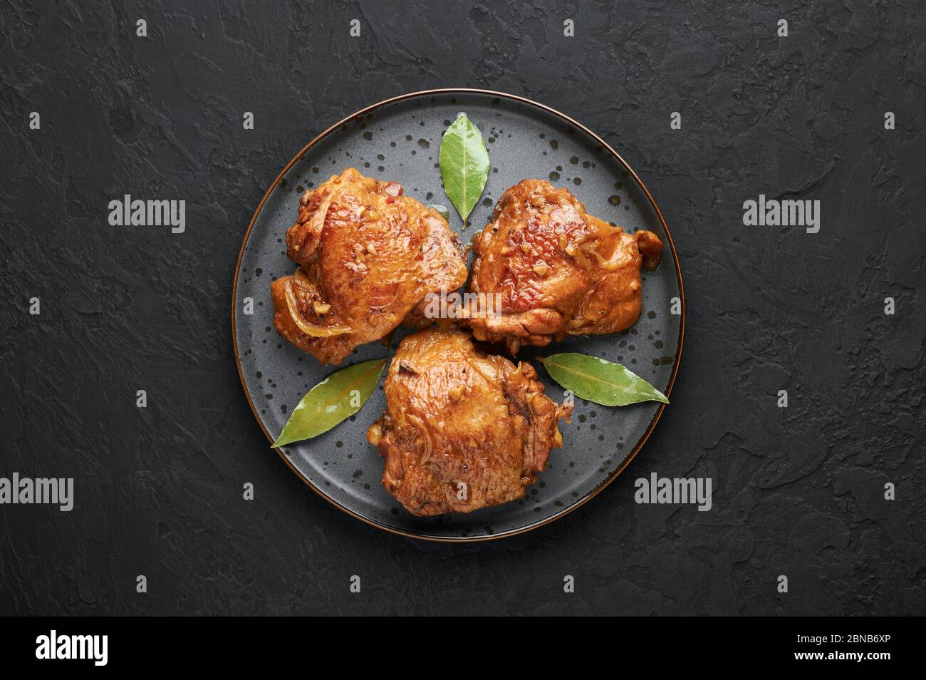 Filipino Chicken Adobo on dark gray plate on black slate backdrop ...