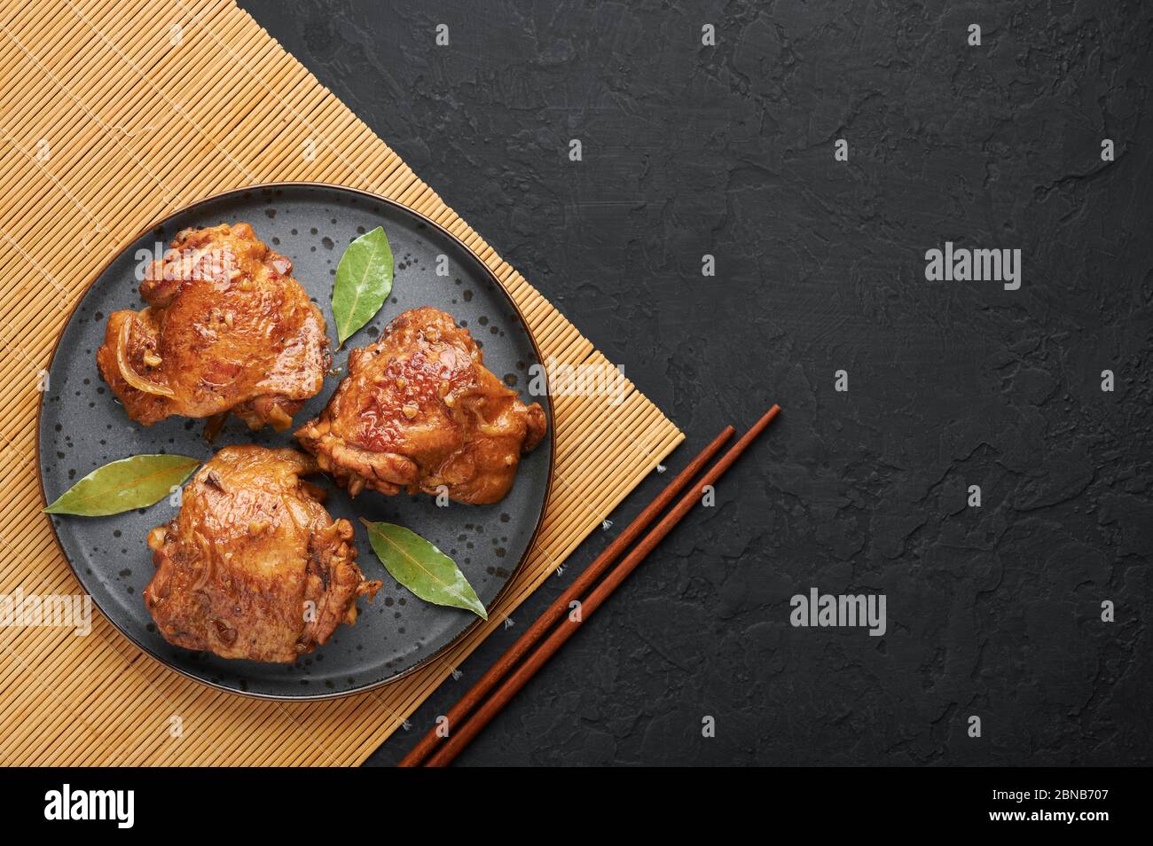 Filipino Chicken Adobo on dark gray plate on black slate backdrop ...