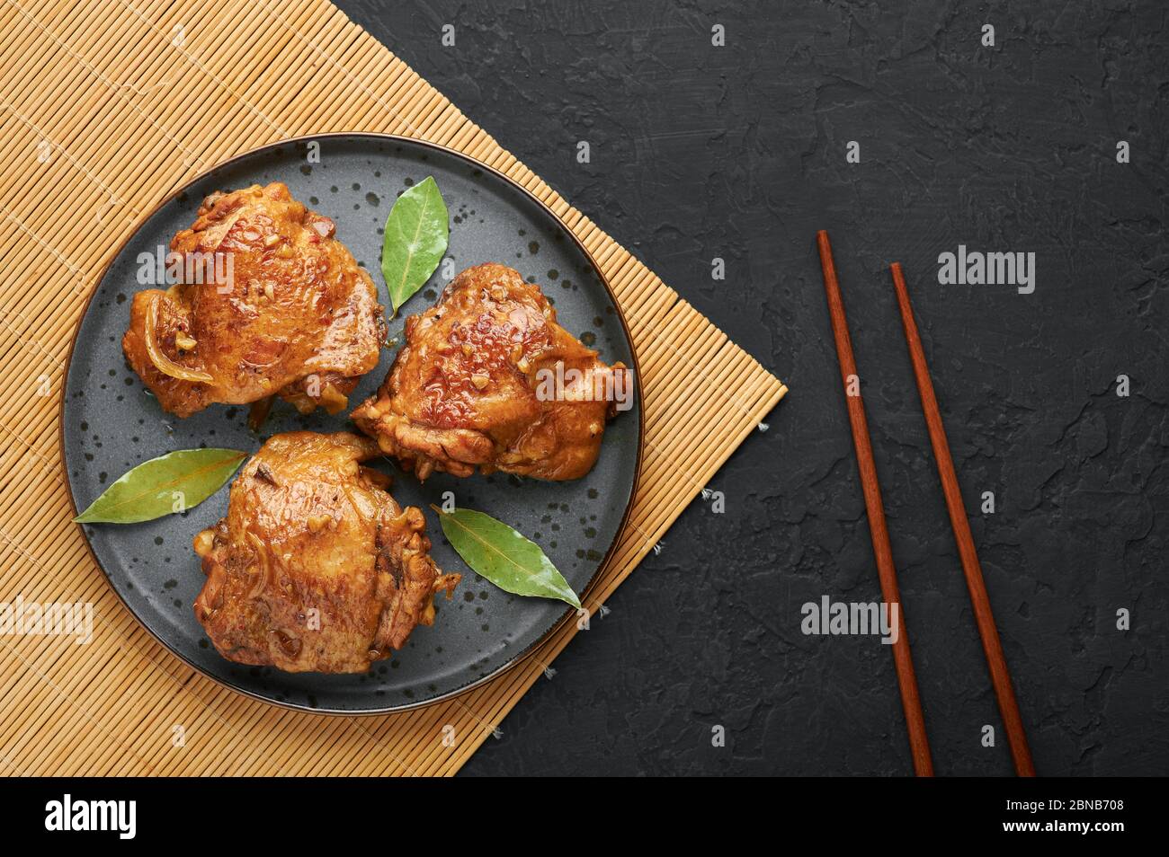 Filipino Chicken Adobo on dark gray plate on black slate backdrop ...