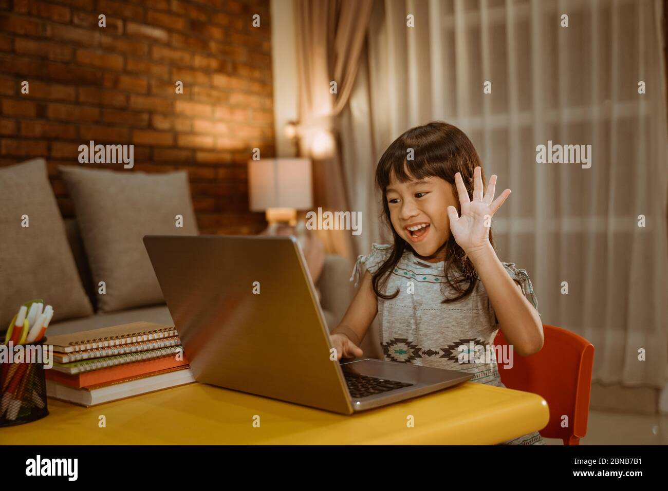 little kid video calling using laptop at home in the evening with ...