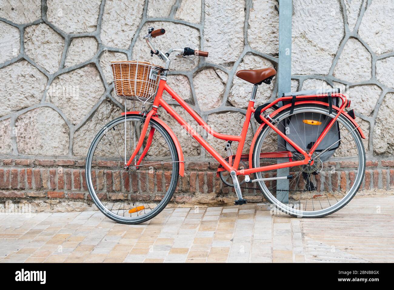Red city bicycle with a basket standing on old street with square ...
