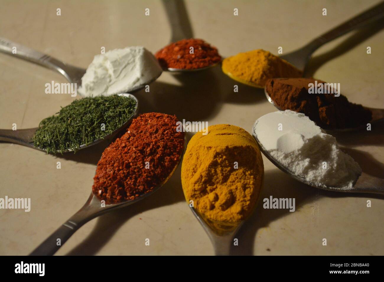 Different kinds of colorful spices in spoons in a circular shape on a ...