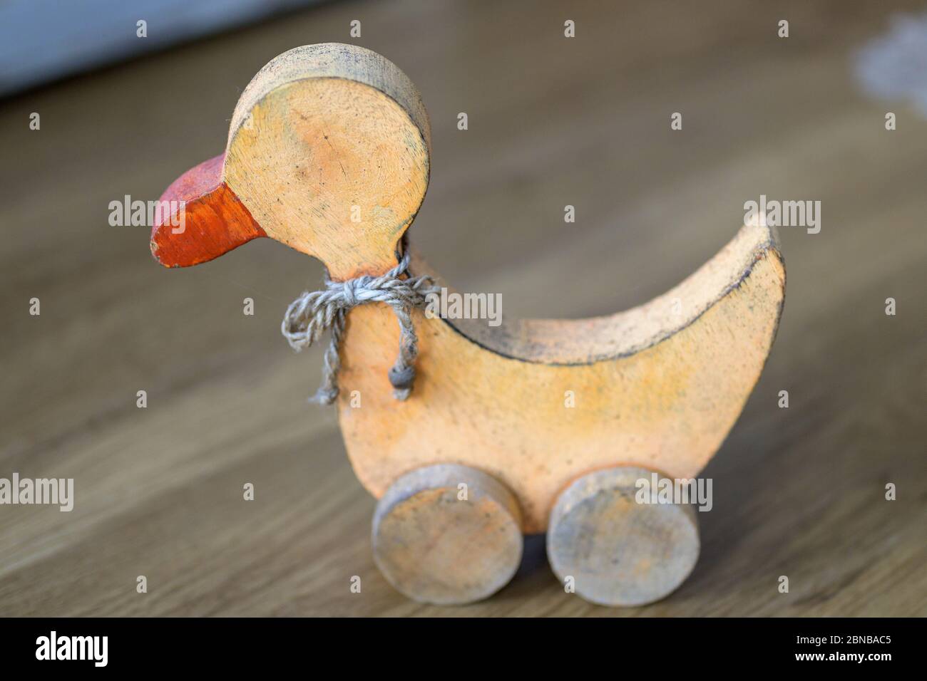 Vintage wooden handcrafted duck toy on wheels with string around its ...