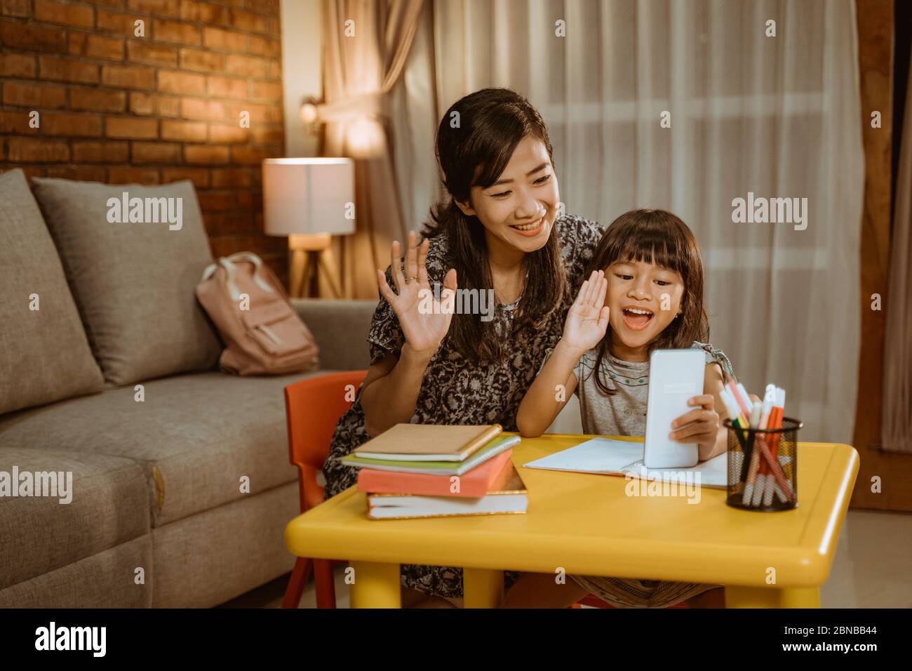 mother and daughter calling with video conference using smartphone in ...