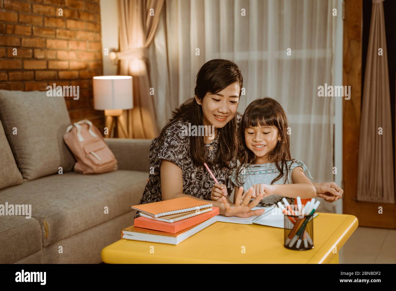 child do homework at home in the evening. mother help her daughter to ...