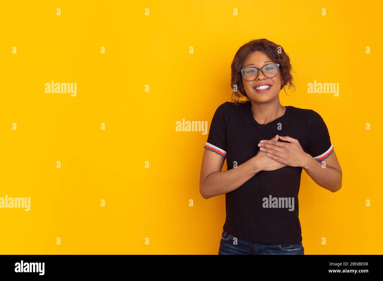 Delighted, shy, hands on heart. African-american young woman's portrait ...