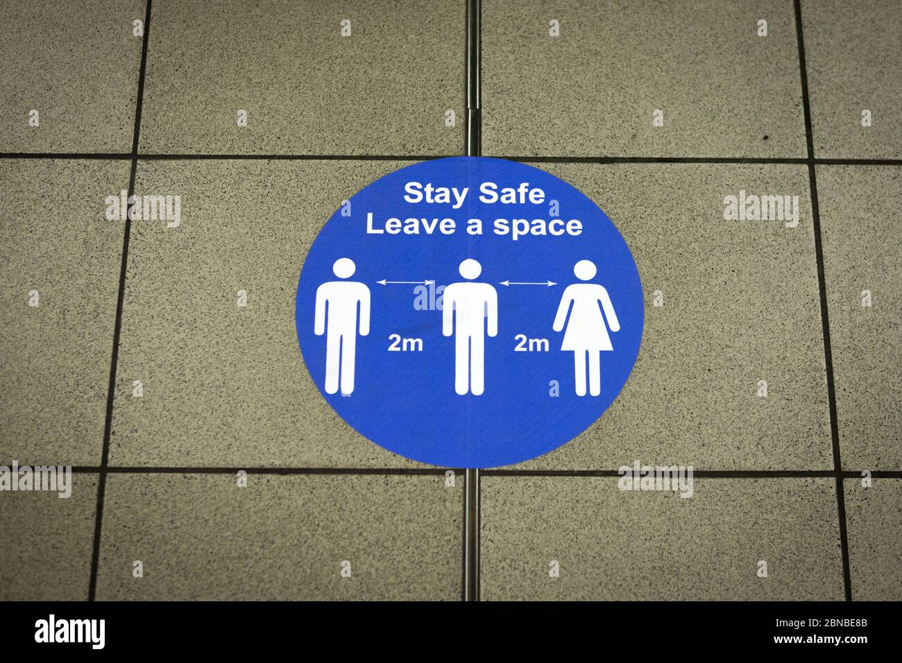 Stickers on the ground reminding passengers to "leave a space" of two ...