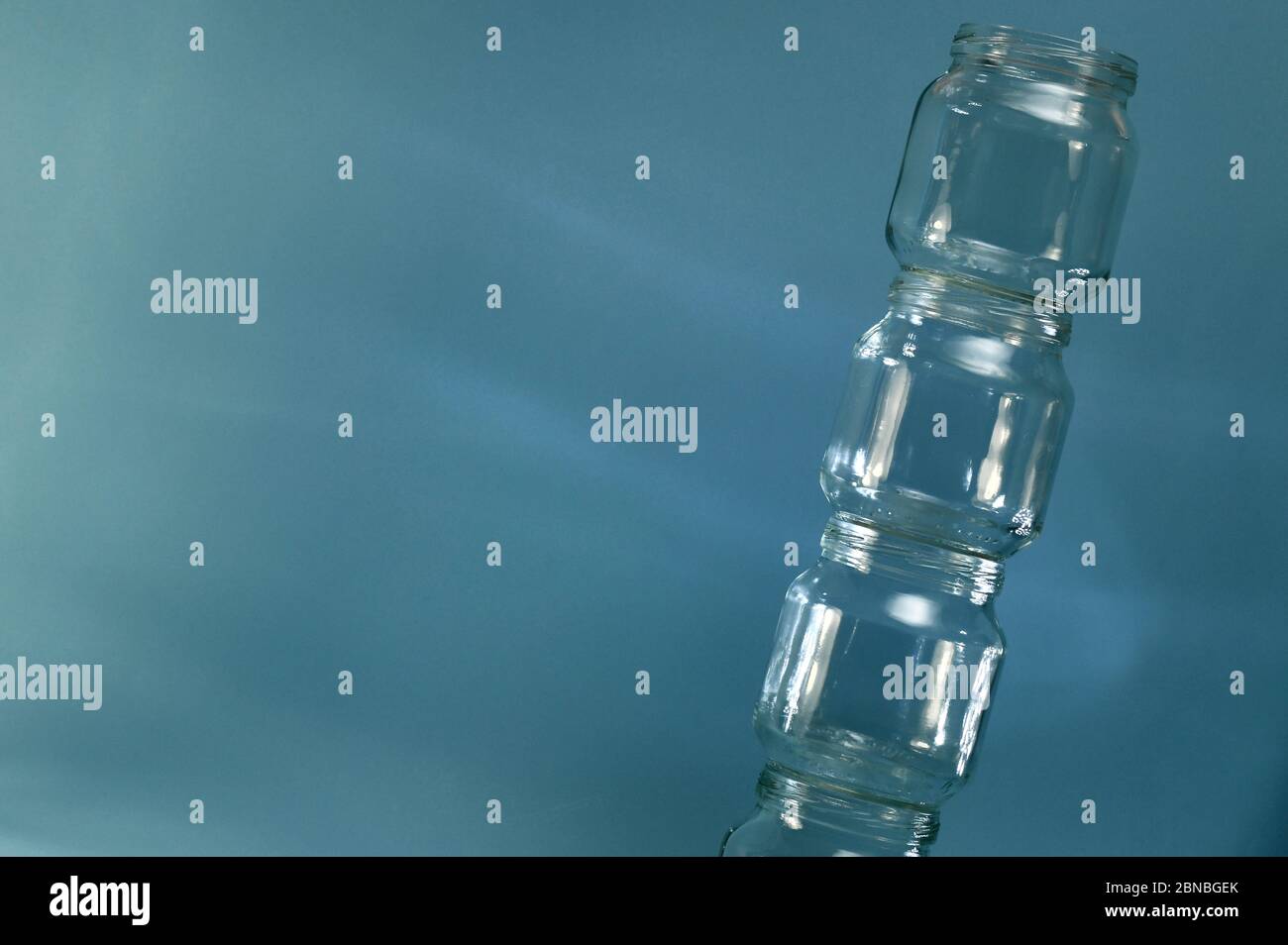 Vertical row of falling glass jars on a blue background Stock Photo - Alamy