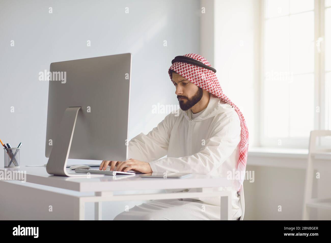 Arab businessman worker with a beard works in computer on the workplace ...