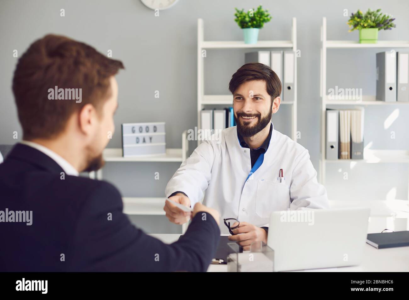Confident doctor gives the patient a prescription while sitting at a ...