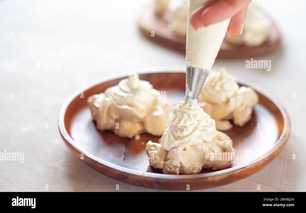 , decorating the meringue with cream from the culinary bag Stock Photo ...