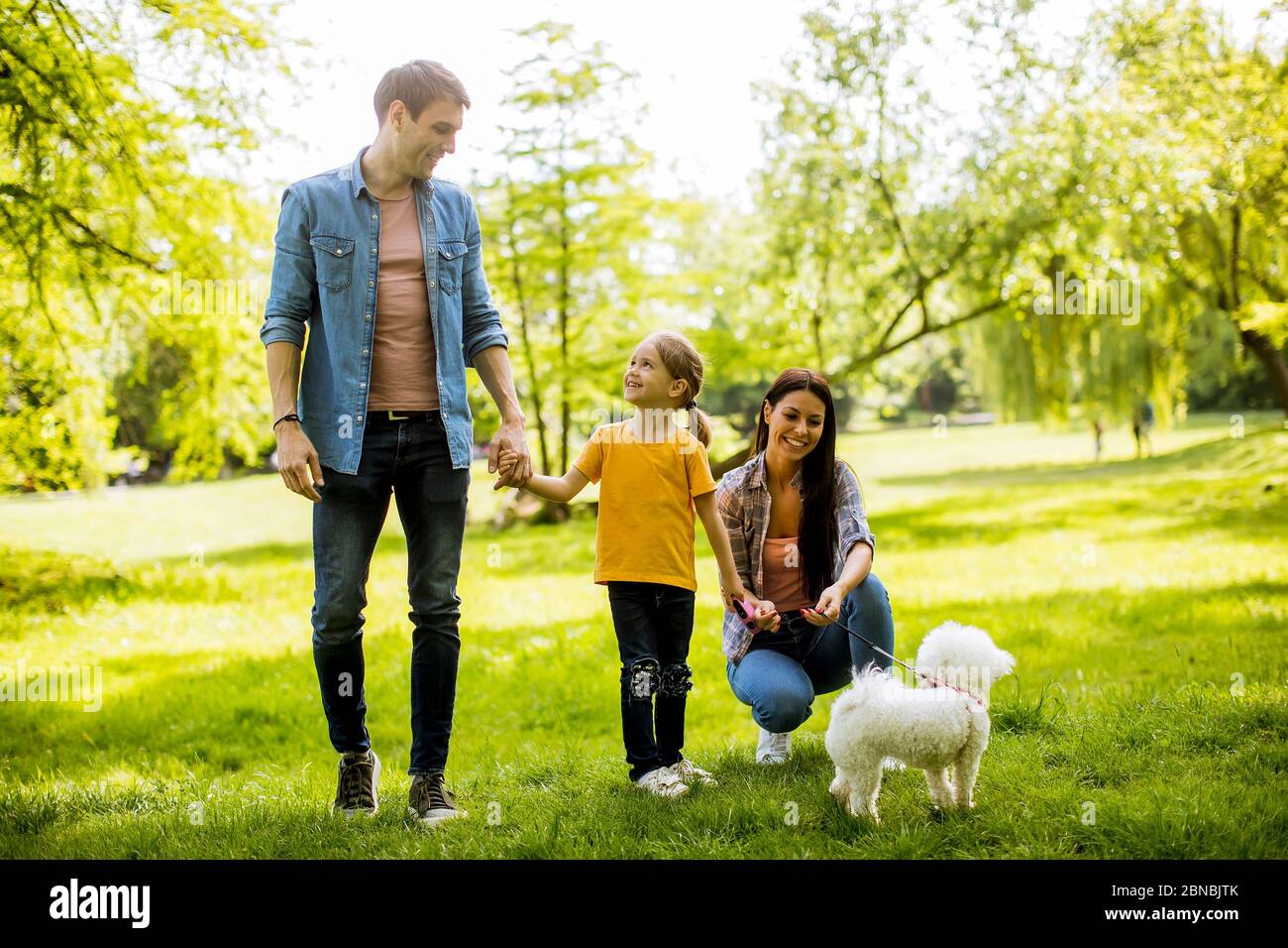 Beautiful happy family is having fun with maltese dog outdoors in the ...