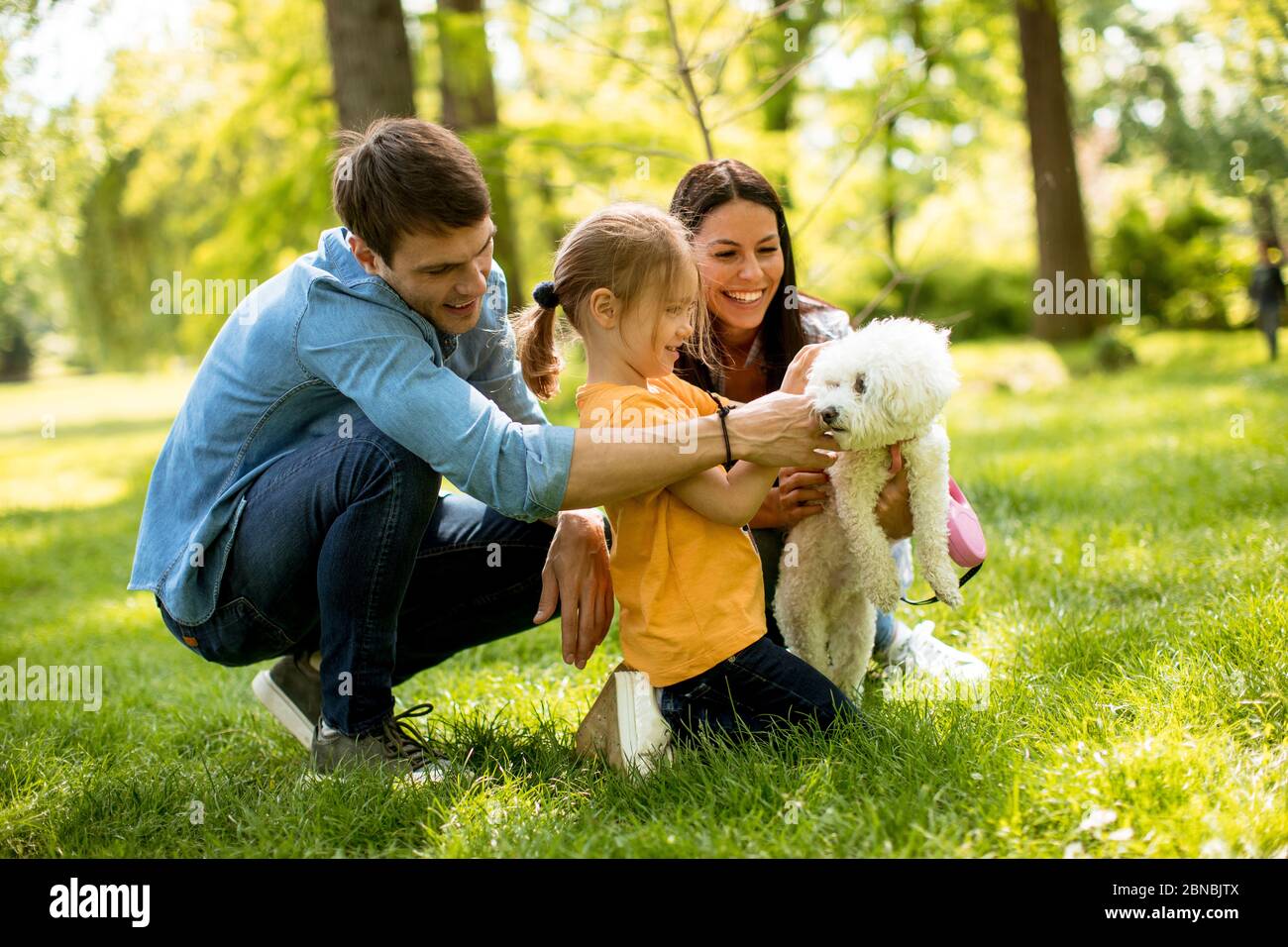 Beautiful happy family is having fun with maltese dog outdoors in the ...