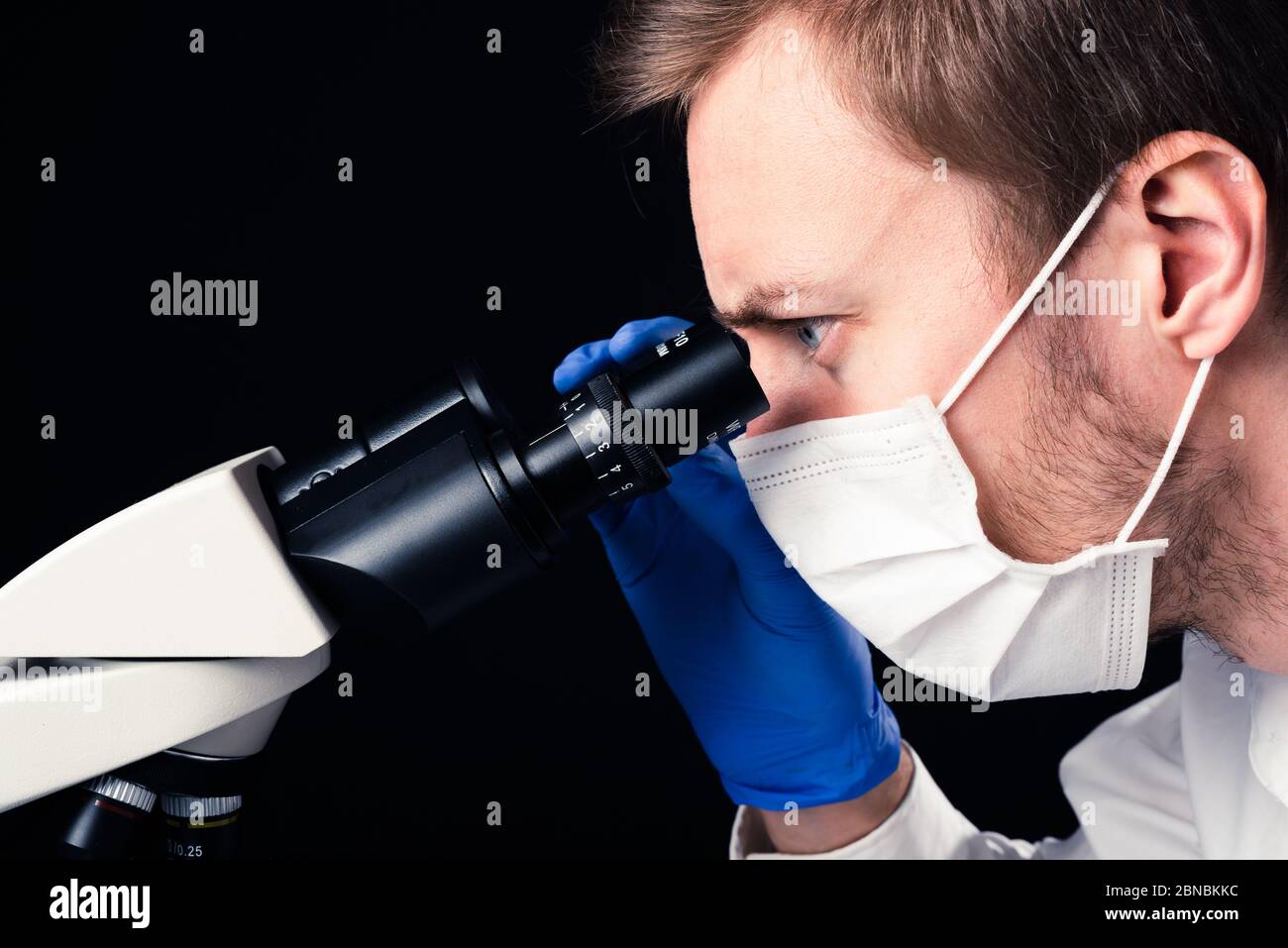 Up-close profile of white male scientist using binocular microscope ...