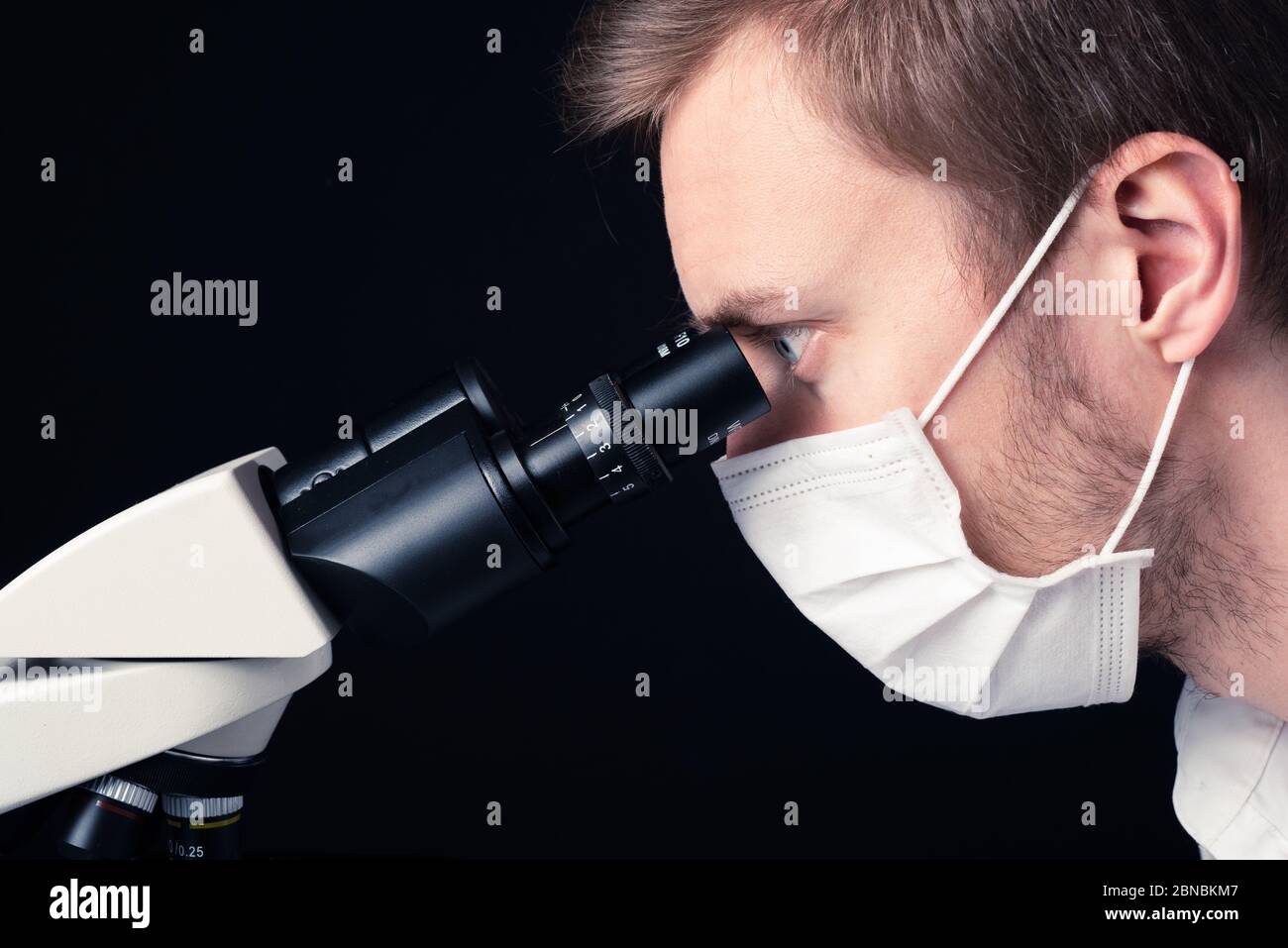 Up-close profile of white male scientist using binocular microscope ...