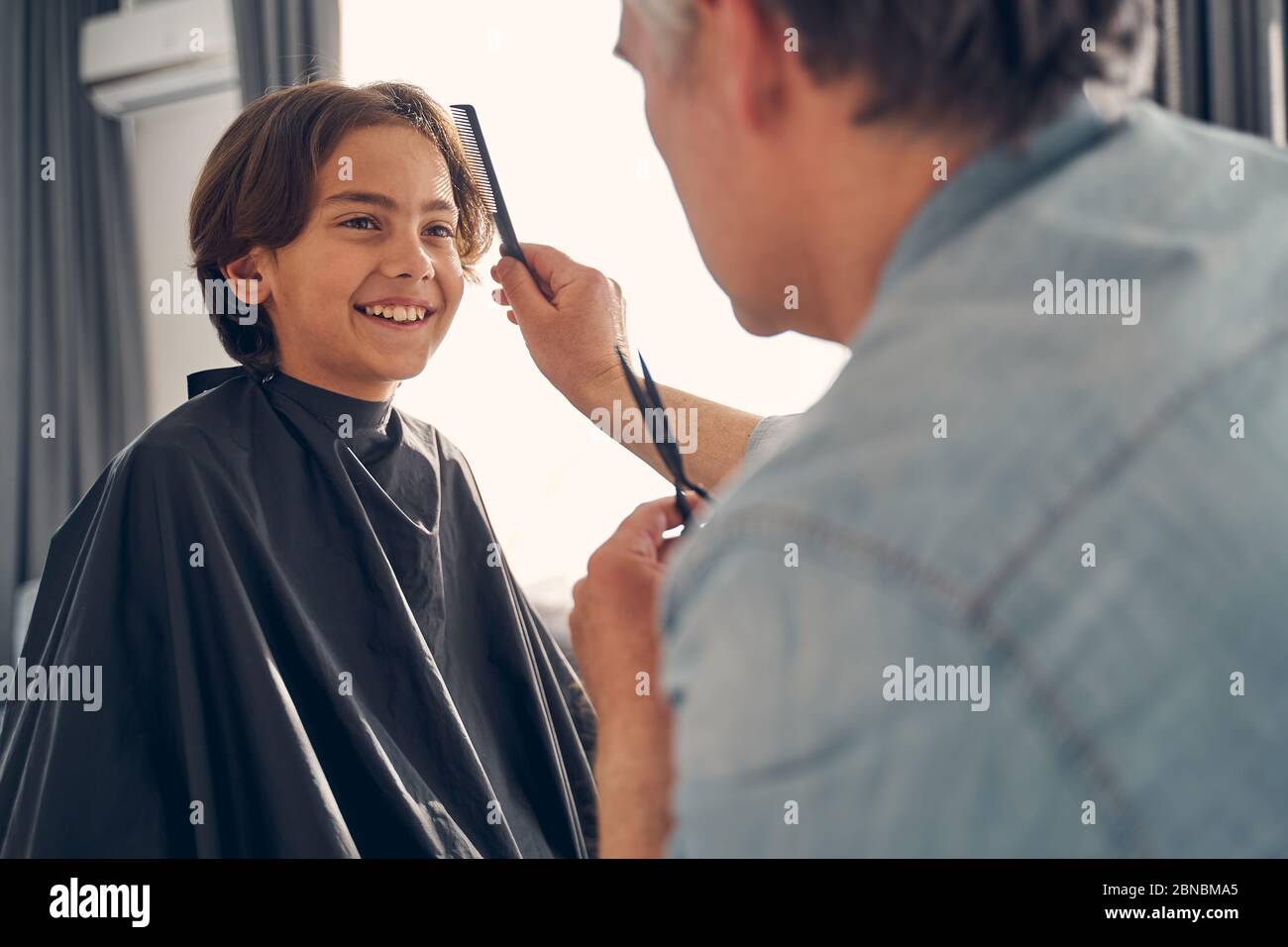 Cutie brunette boy smiling at man opposite him Stock Photo - Alamy